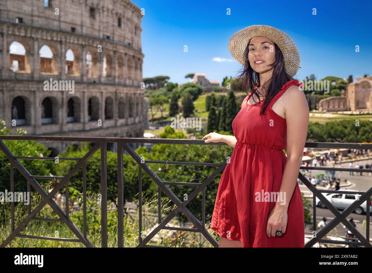 Brunette girl with straw hat admires the majesty of the Colosseum and ...