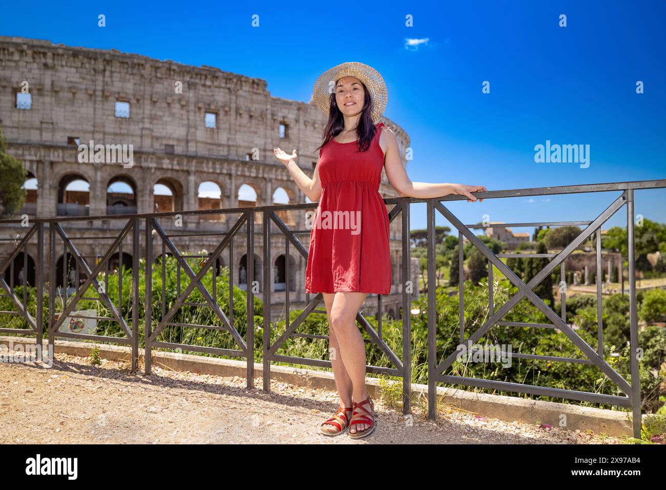 Brunette girl with straw hat admires the majesty of the Colosseum and ...
