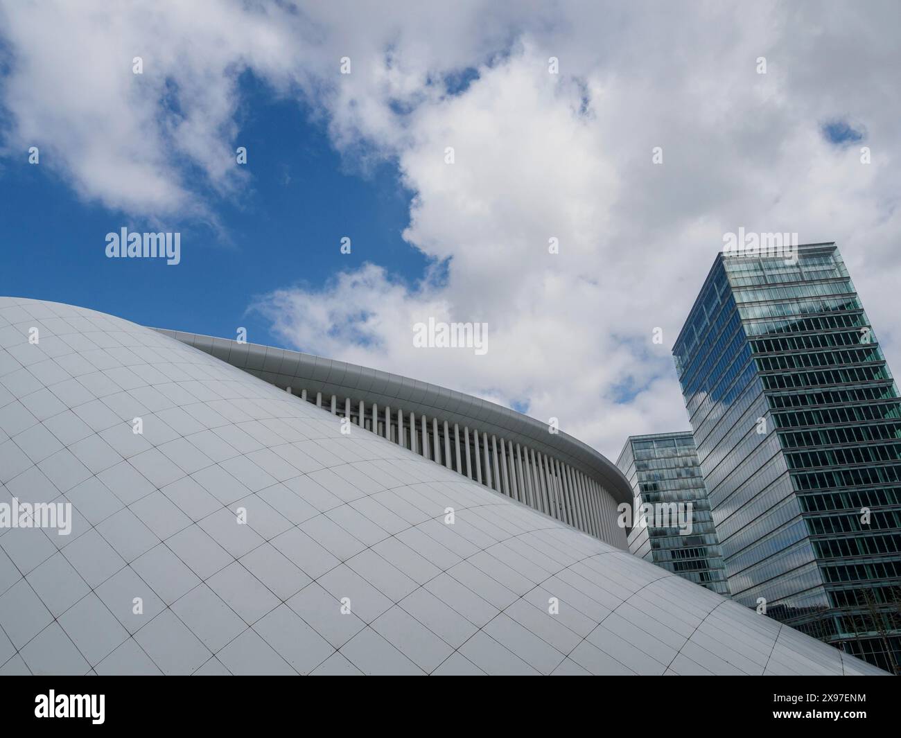 Arched white structure and glass facades of skyscrapers under a blue ...