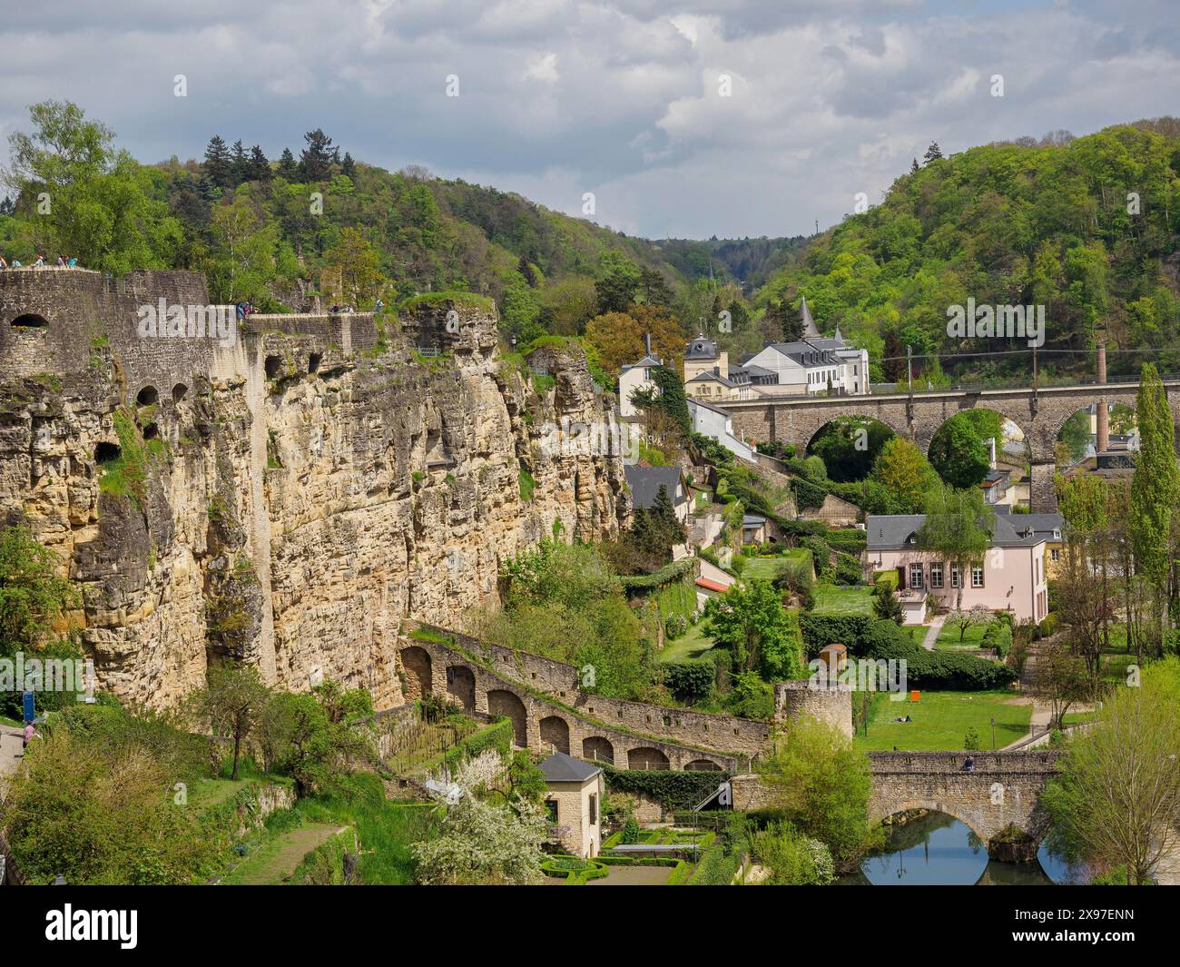 Rocky cliff landscape with a bridge, buildings and lush greenery around ...