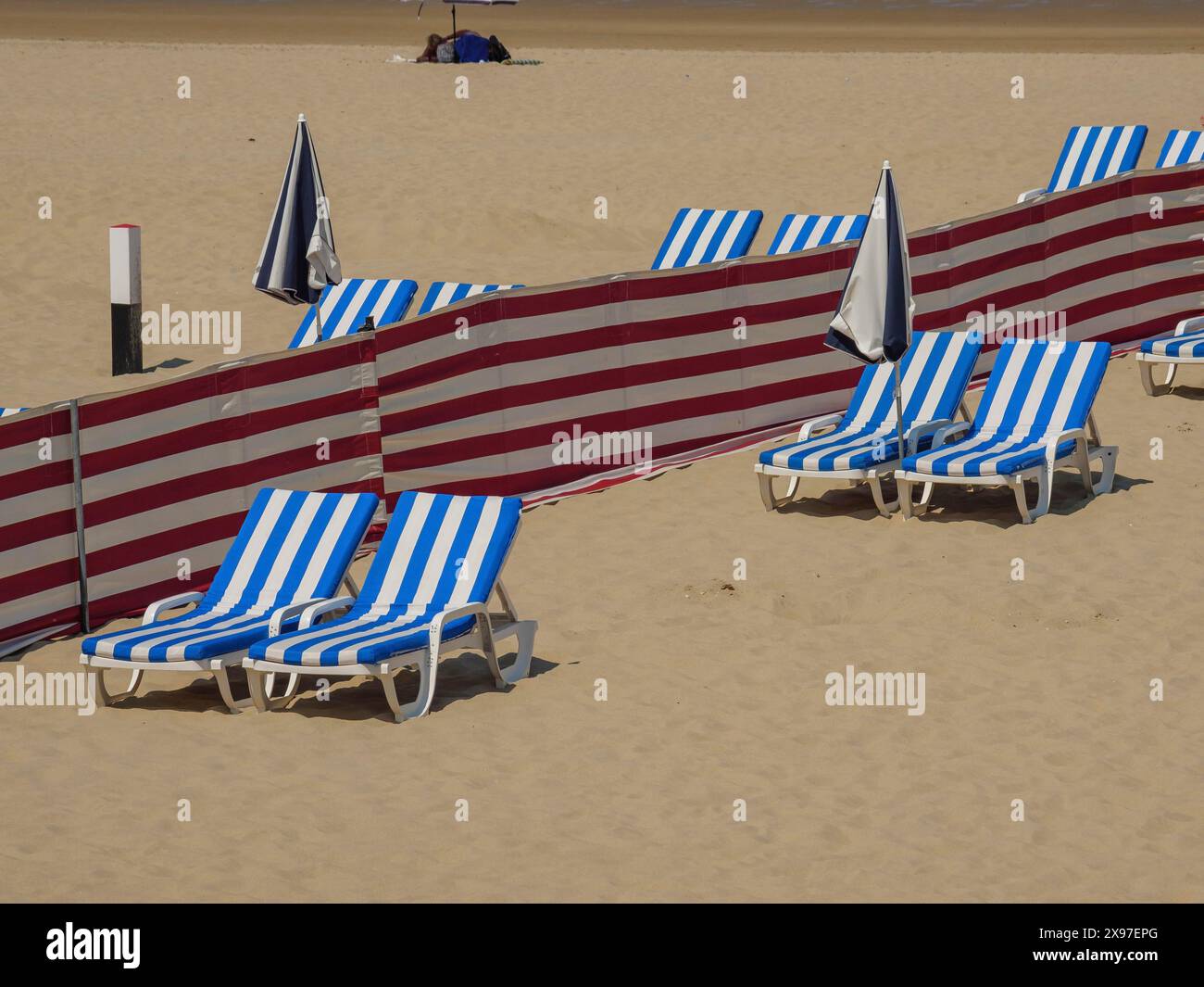 Beach where blue and white striped deckchairs, parasols and red ...