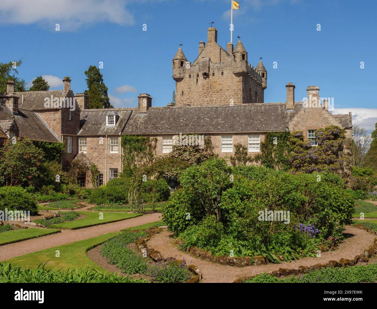 Medieval castle with towers and well-kept garden area under a blue sky ...