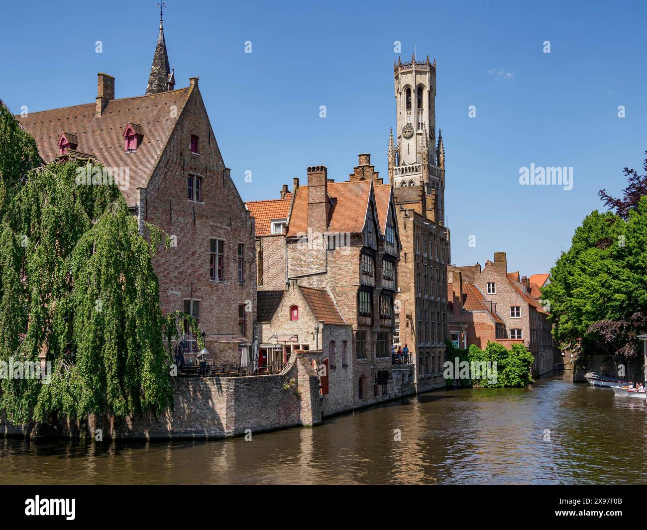Historic buildings and a tall bell tower along a river on a sunny day ...