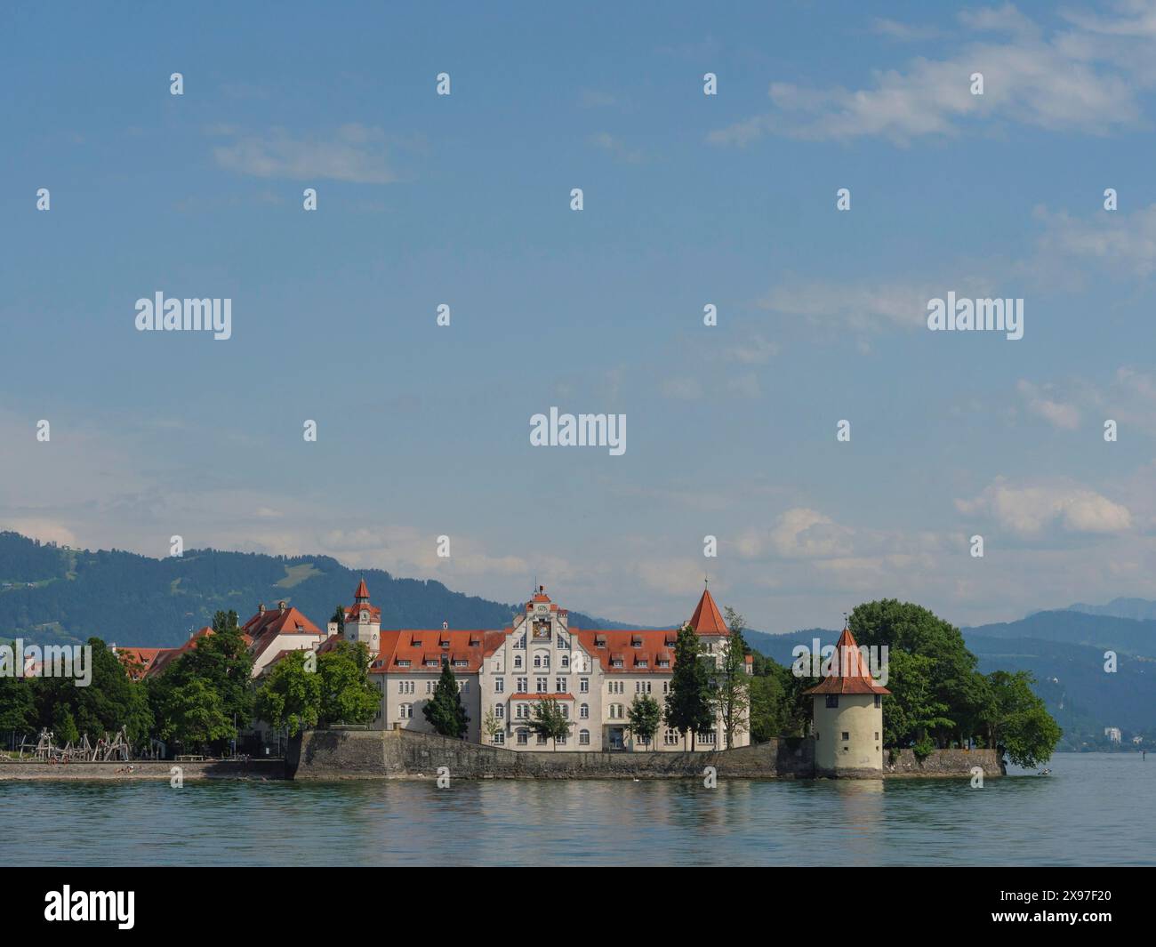 A castle with red roofs on a lake, surrounded by trees and mountains in ...