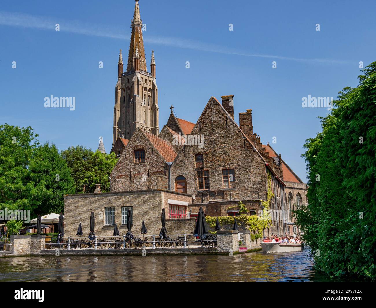 A large old brick church building with green plants and boats by the ...