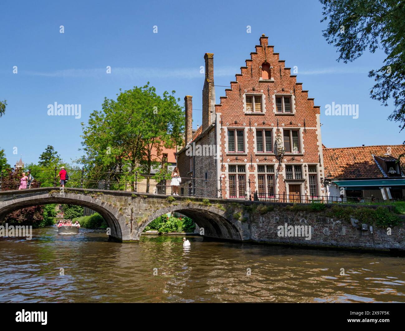 An old stone bridge over a river flanked by a historic building and ...