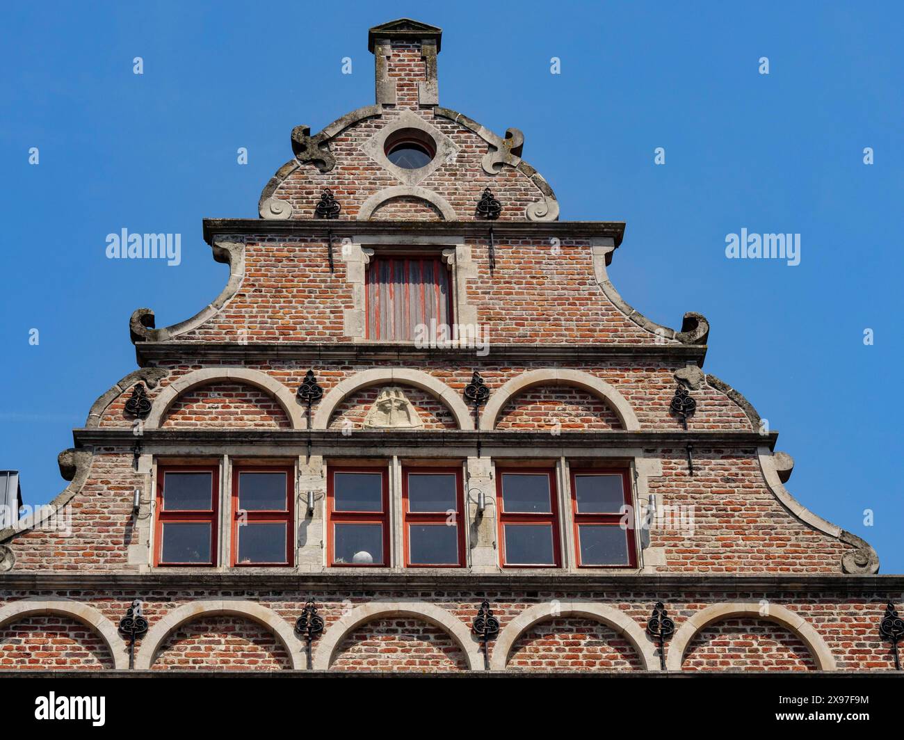 Historic house with elaborate brick facade and windows under a blue sky ...