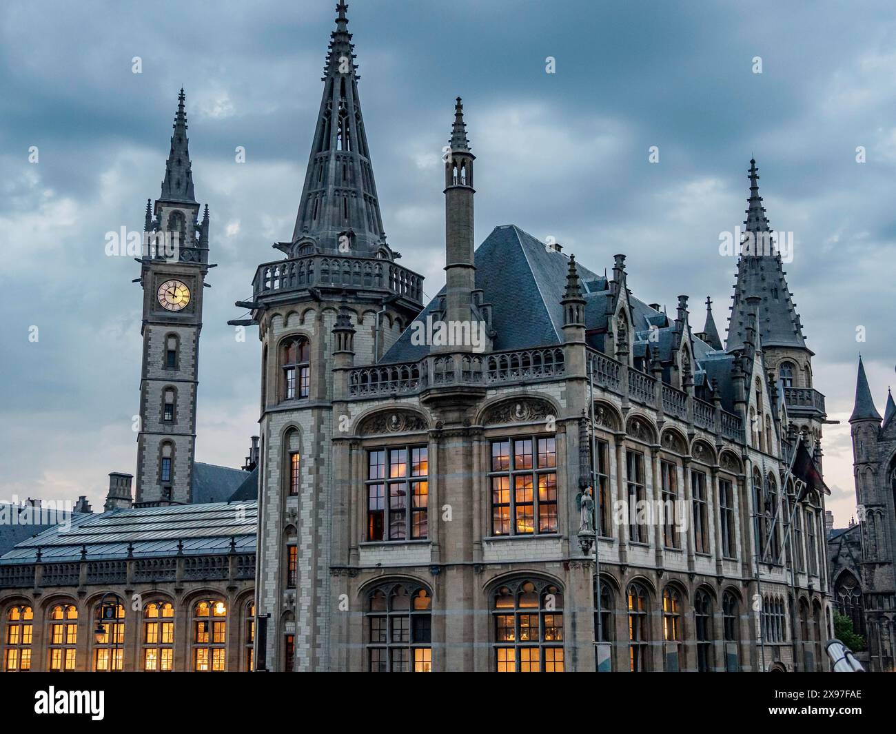 Gothic buildings with dominant towers and a clock tower, illuminated in ...