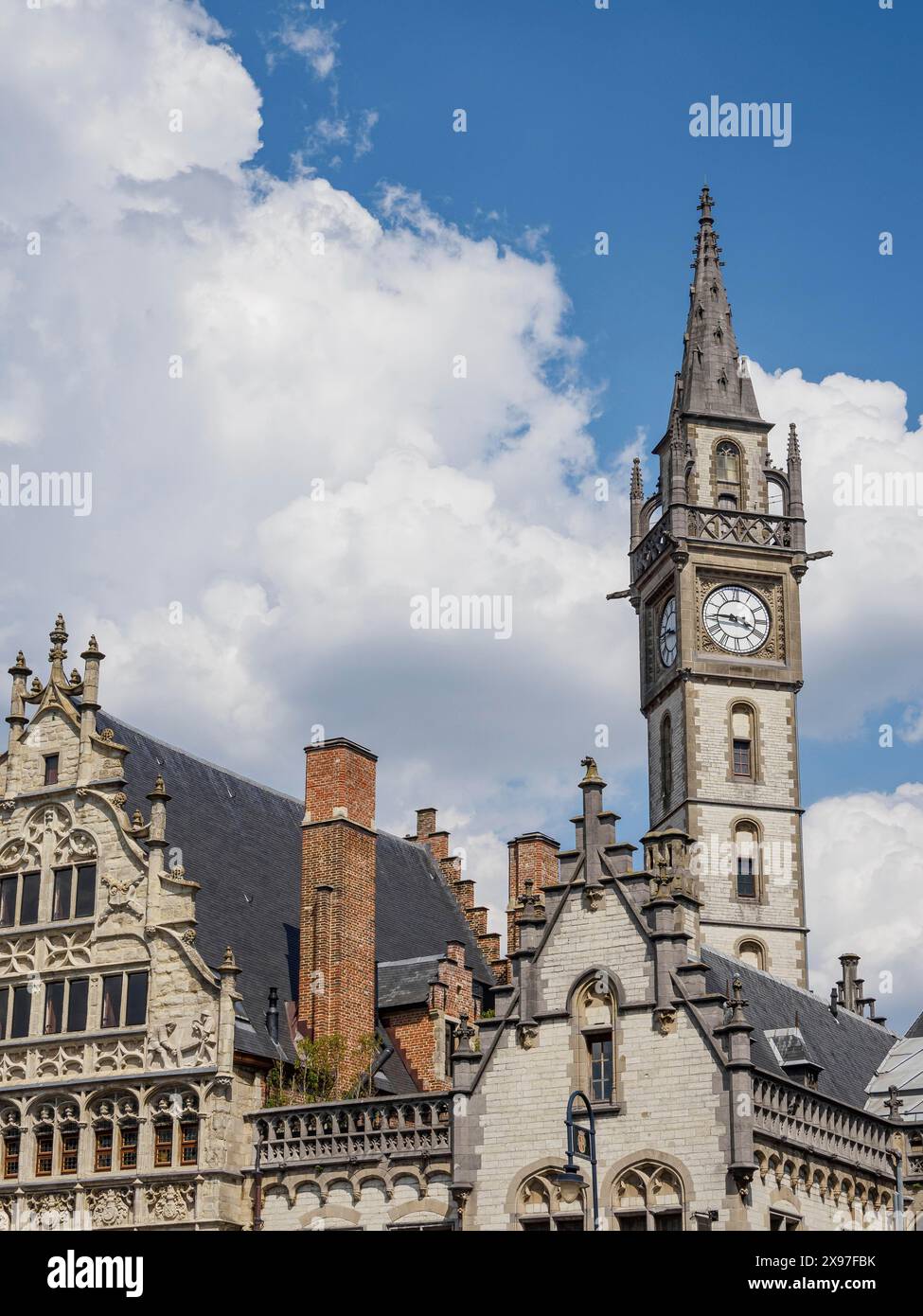 Clock tower and gothic buildings with ornate facades under a blue sky ...