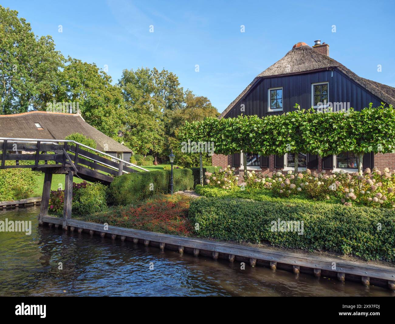 A charming house with flowering garden and wooden bridge next to a ...
