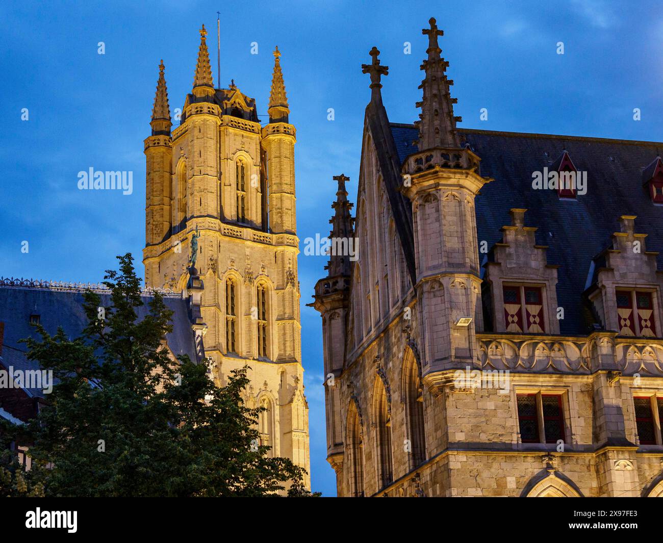 Gothic church tower and building facades, illuminated at dusk, blue ...