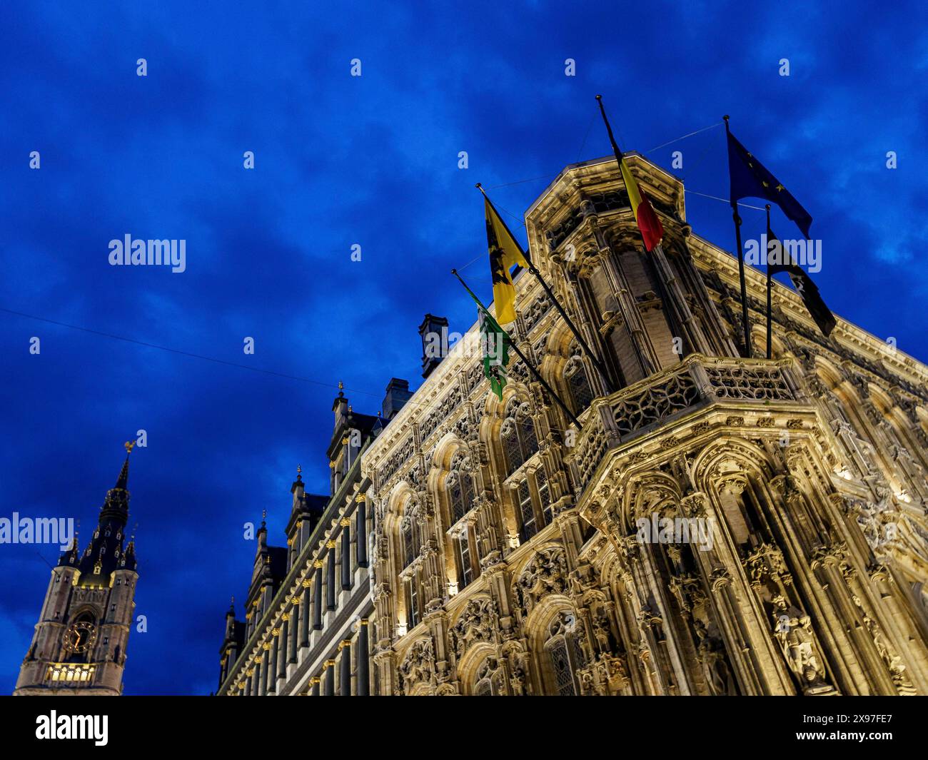 Illuminated building with ornate details and flags against a deep blue ...