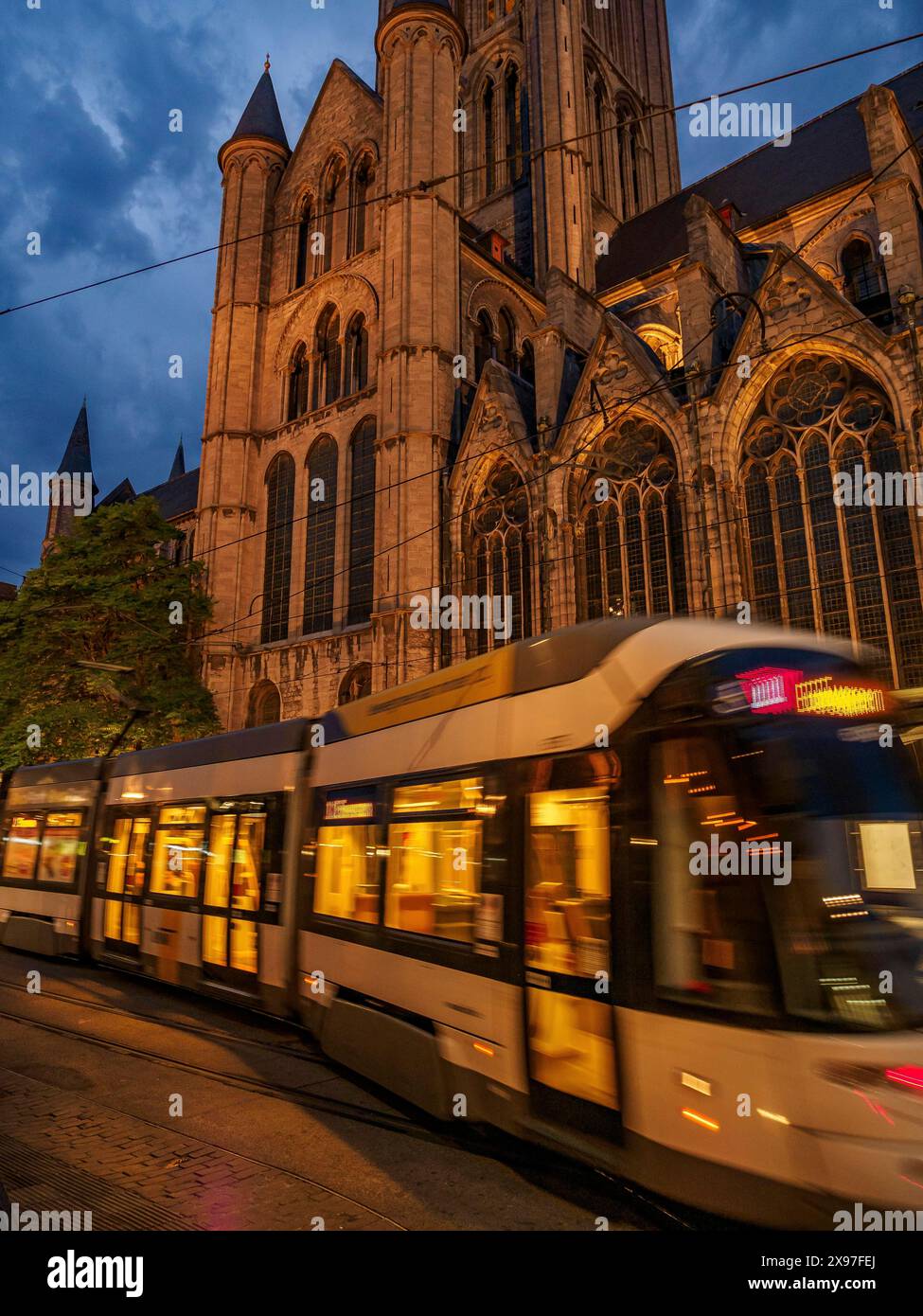 Moving tram in front of a gothic cathedral at dusk in a historic city ...