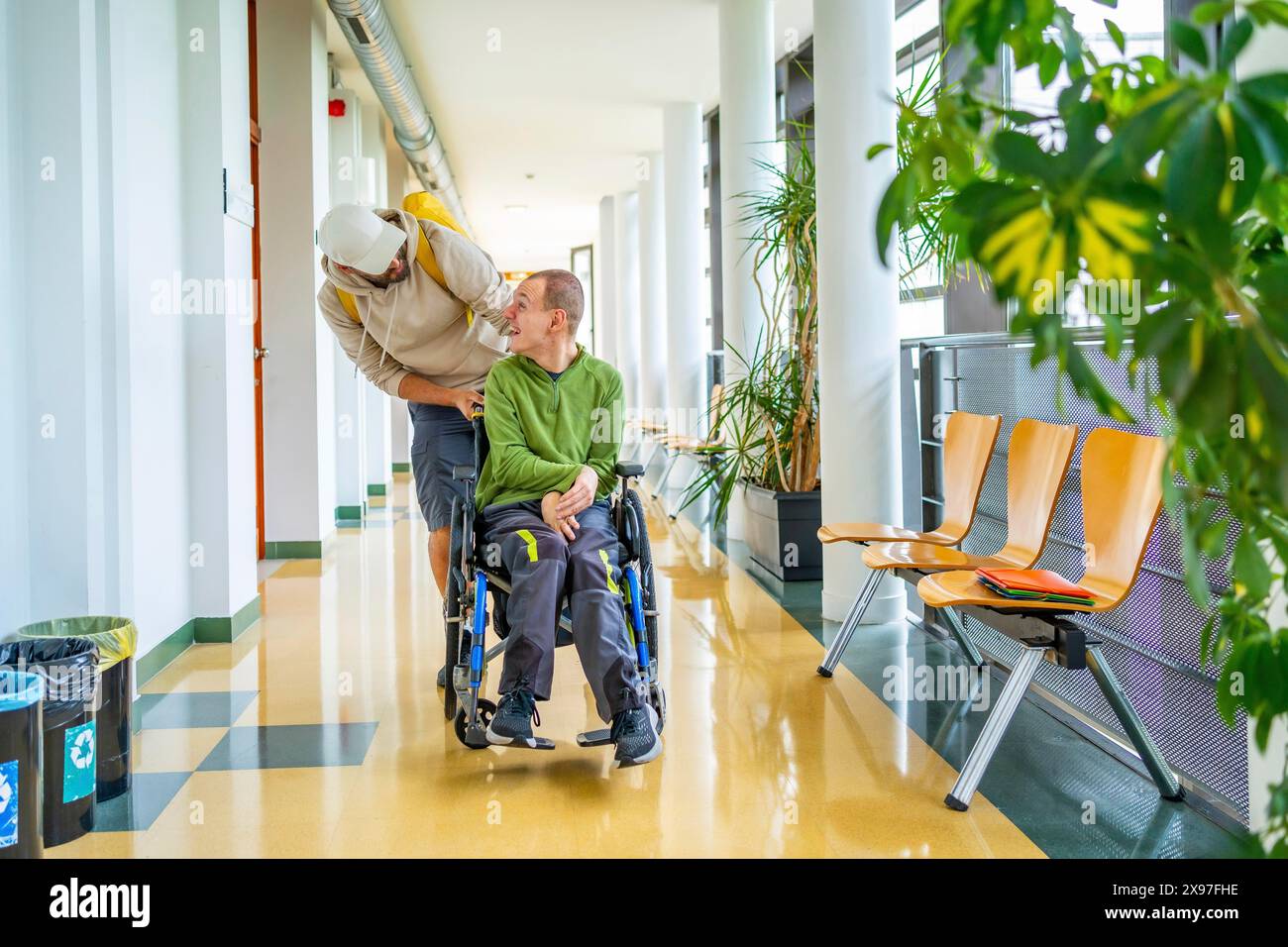 Friend pushing the wheelchair of a disabled man with cerebral palsy in ...