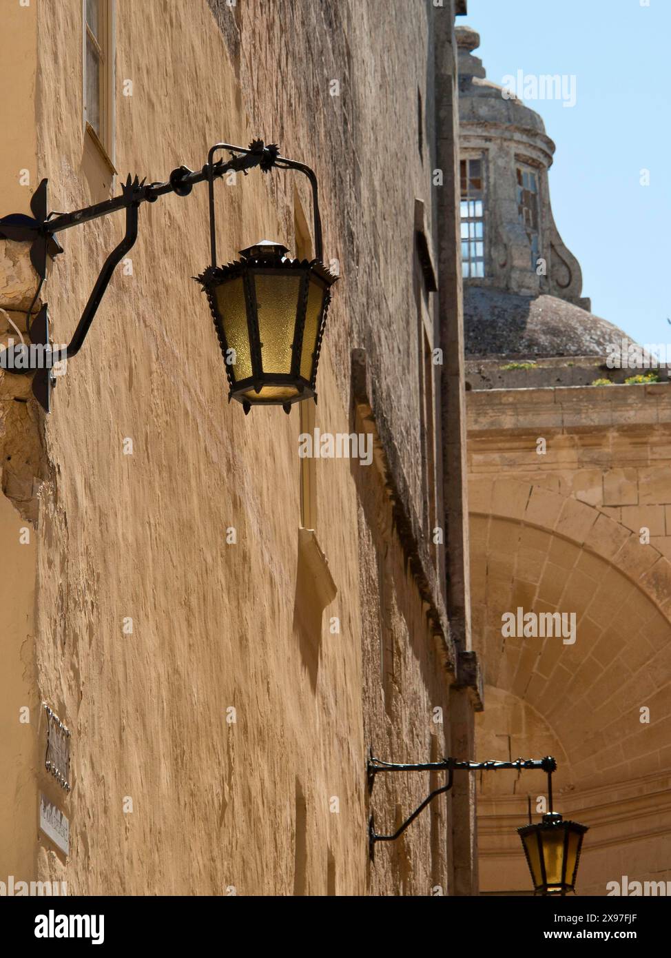 Historic lantern along an old wall with arch structure and blue sky in ...