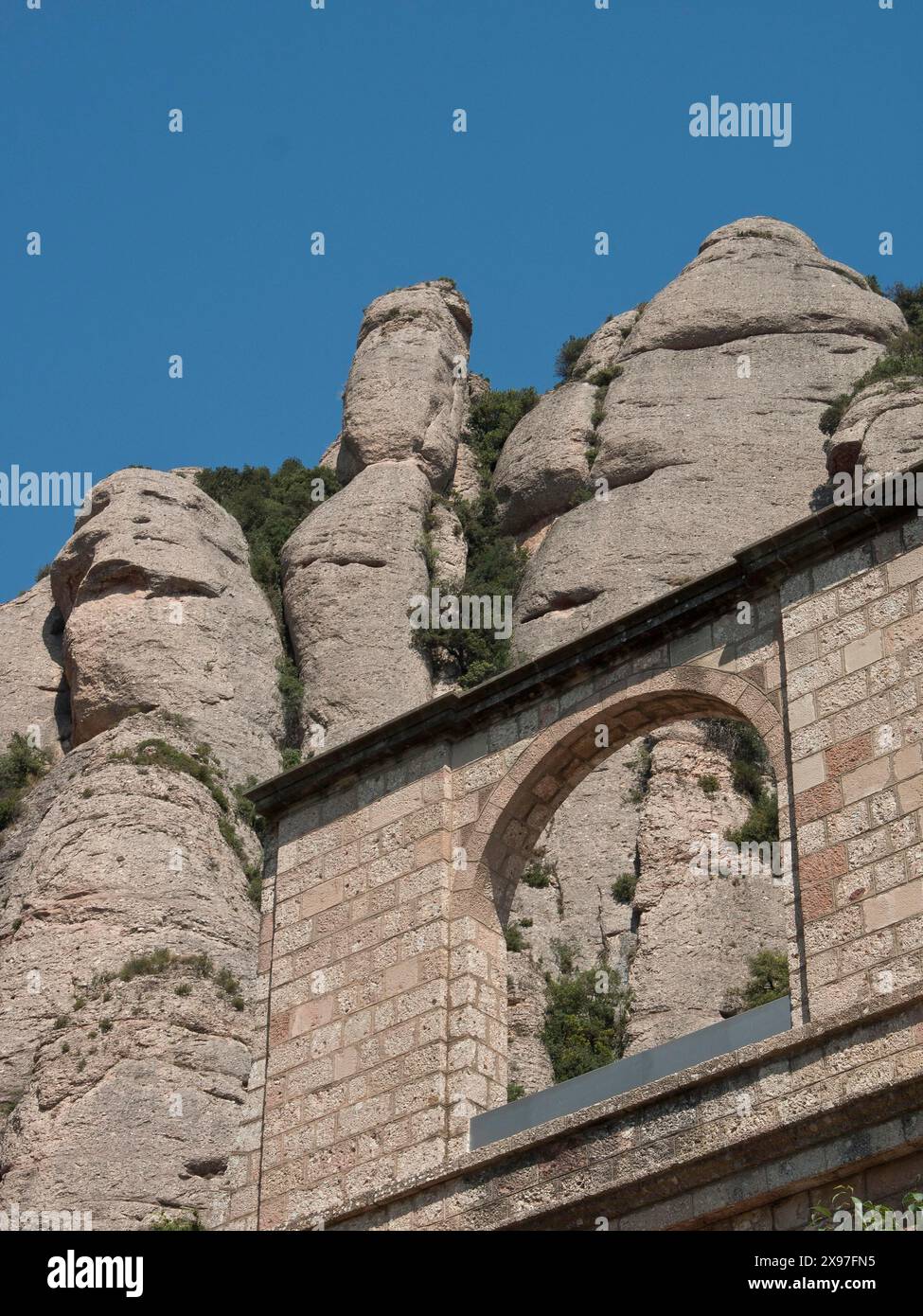 A single stone arch of a ruin in front of overwhelming rocks and blue ...