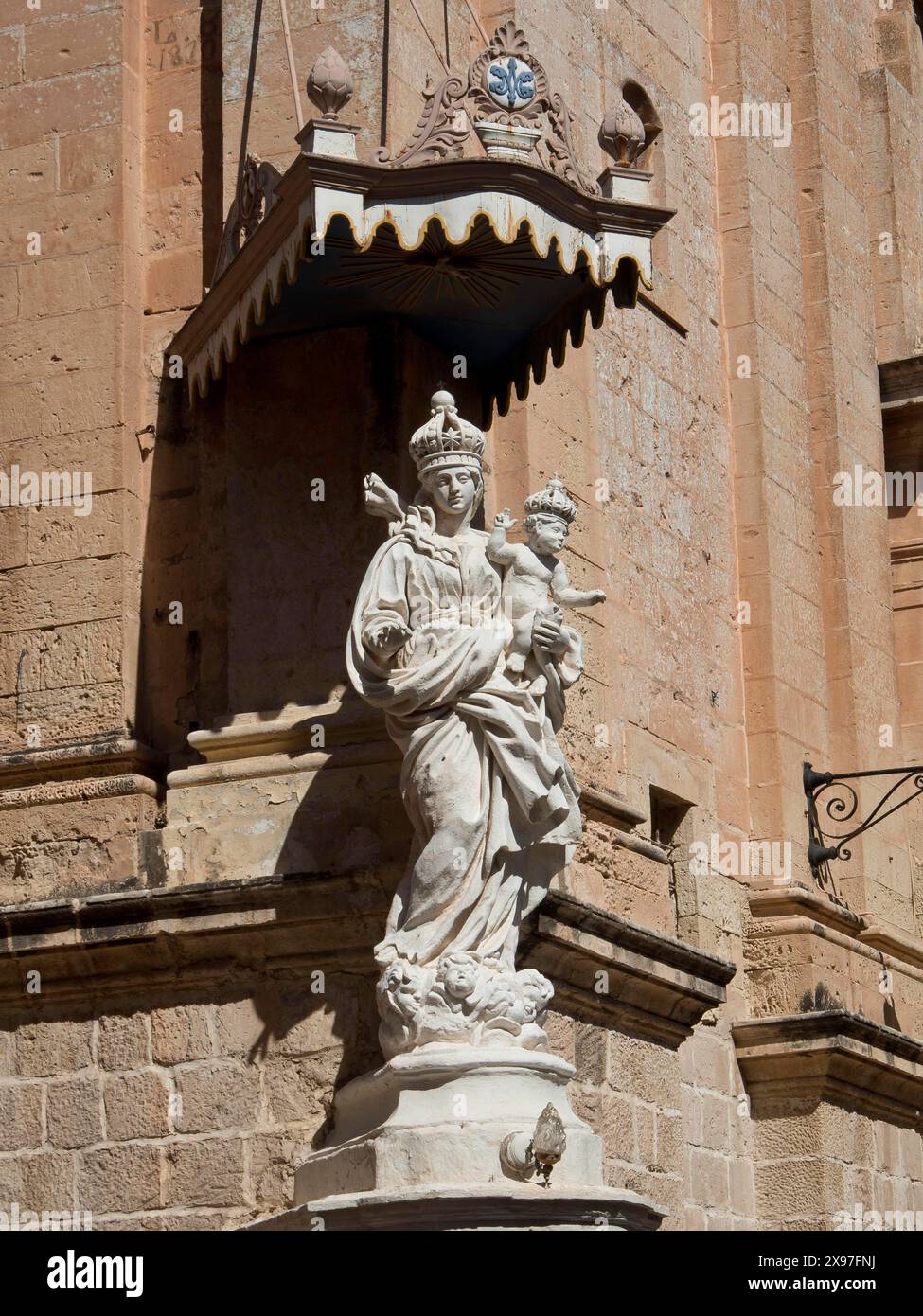 Close-up of a baroque statue on a stone house wall under a blue sky ...
