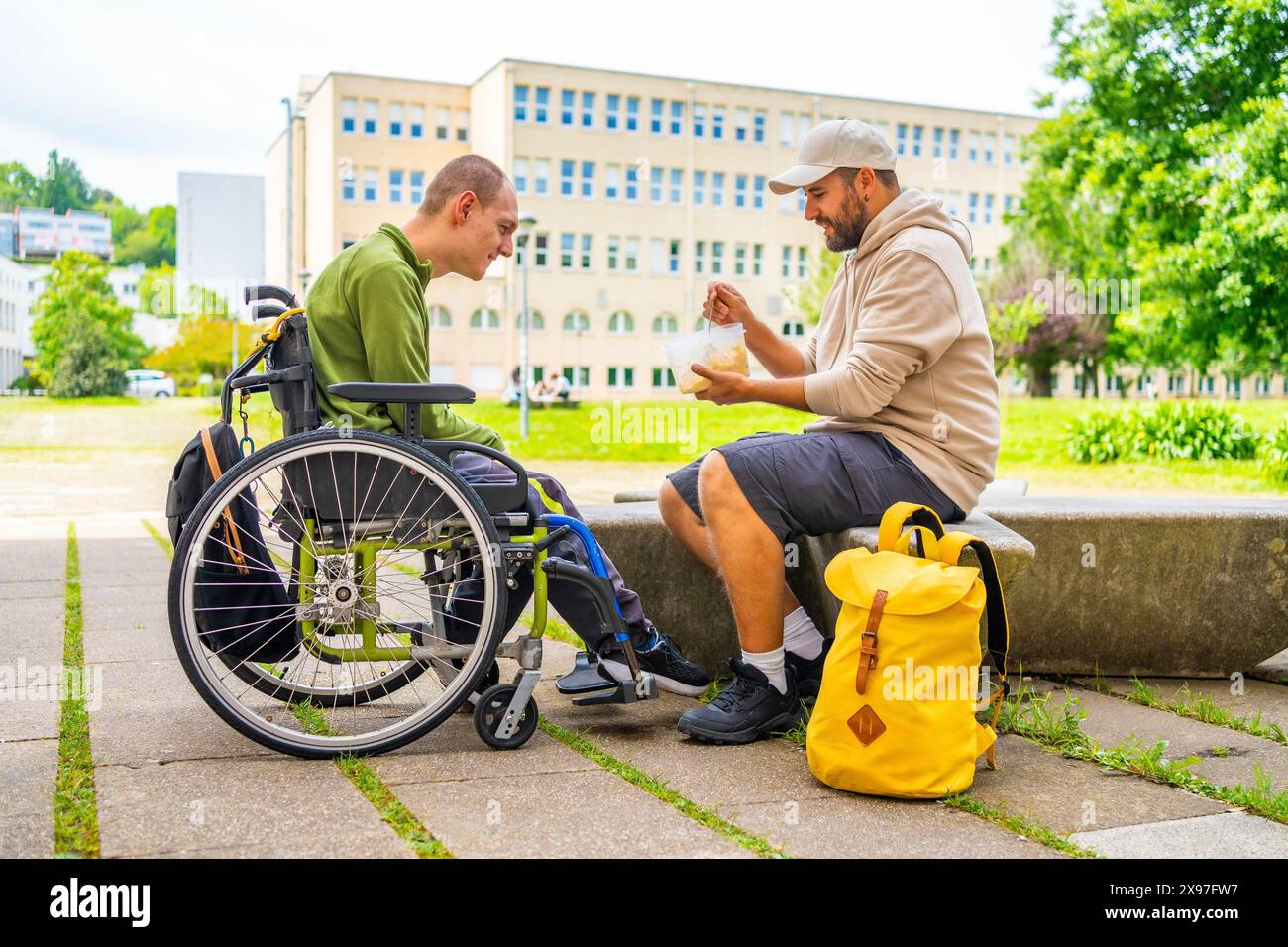 Man helping to eat to a man with cerebral palsy in a wheelchair in the ...