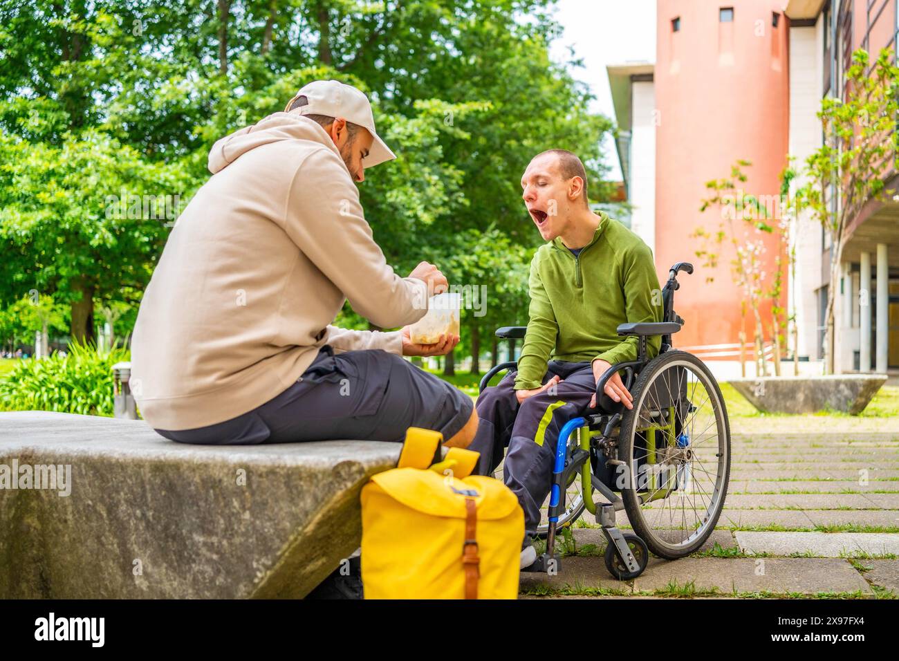 Male caucasian adult university student feeding a friend with cerebral ...