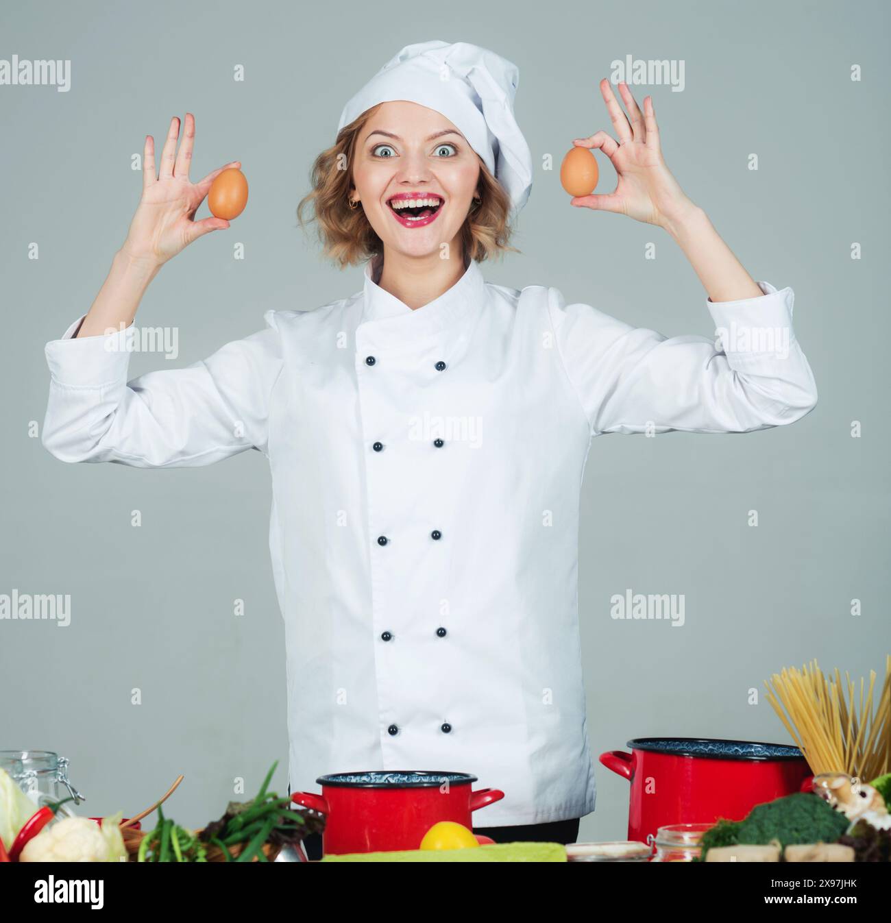 Happy female chef with eggs in hands. Smiling woman in white chef ...
