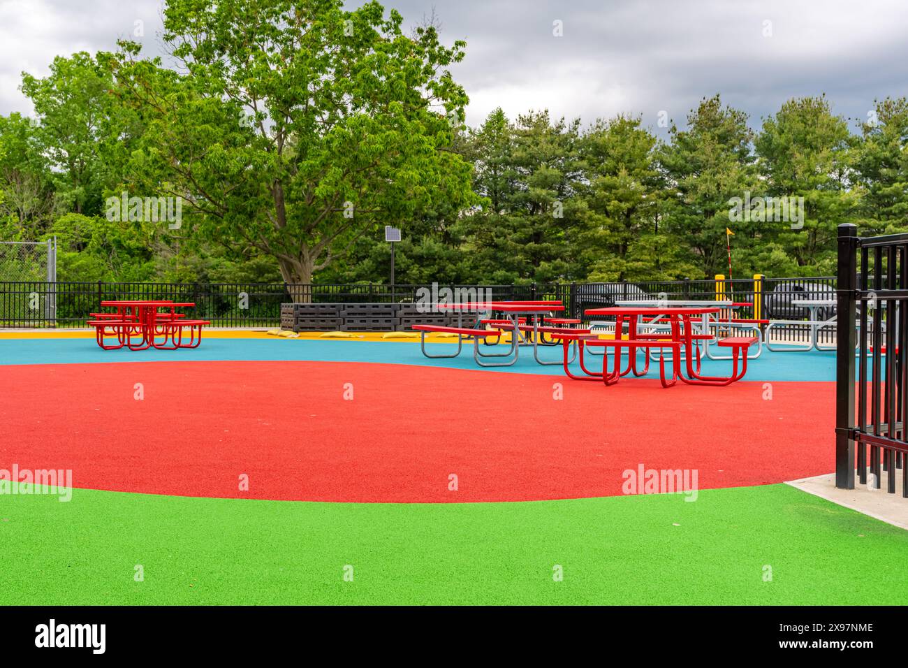 Red vinyl coated picnic table on a multi color playground surface Stock ...