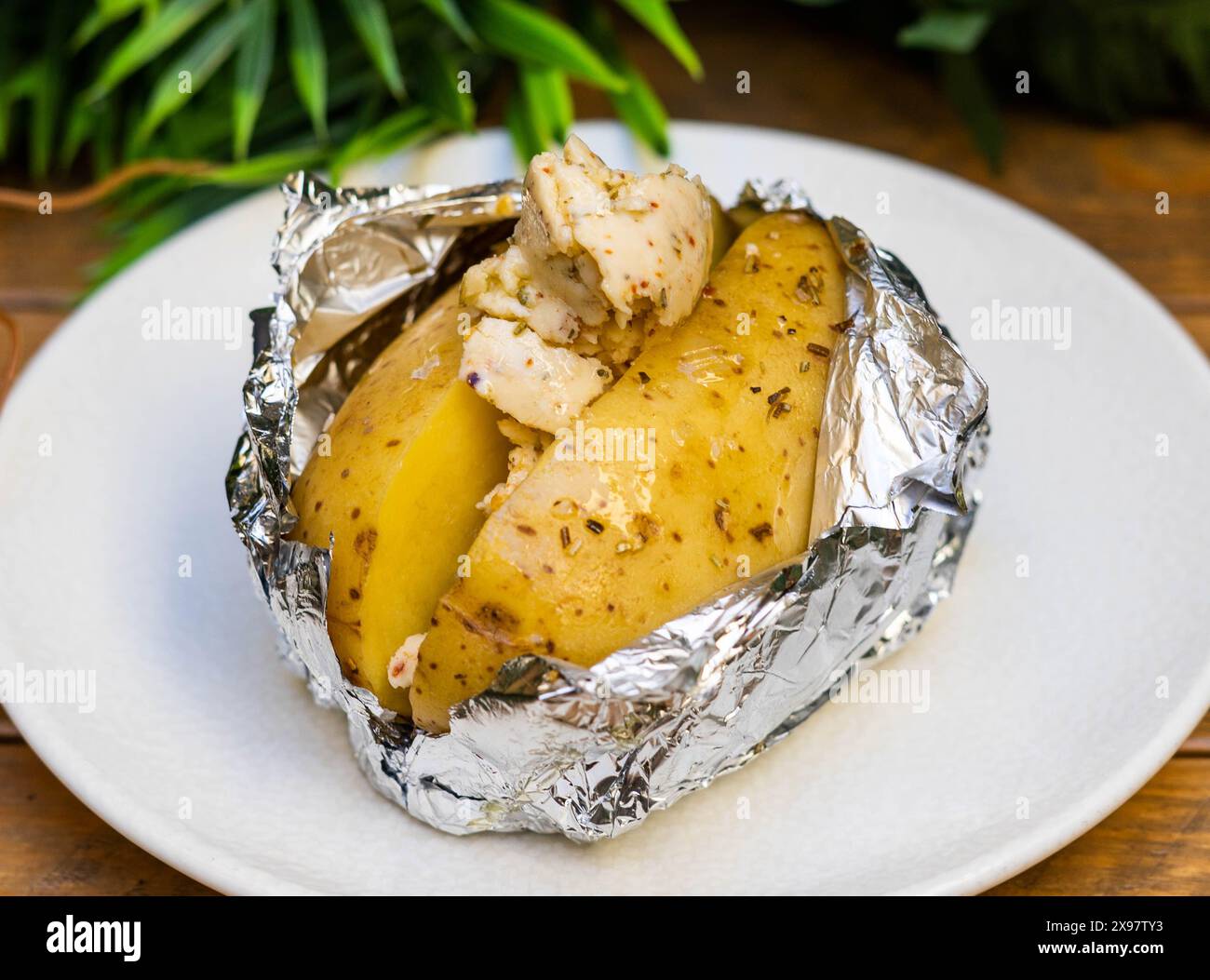 Potato roasted over fire with butter Stock Photo - Alamy