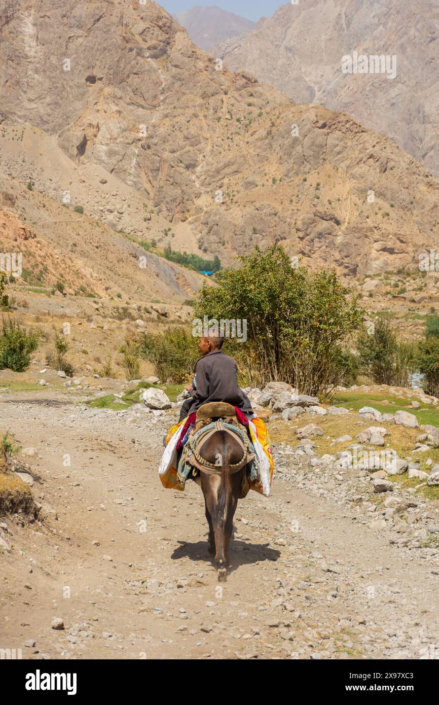Haft Kul, Tajikistan, 21 August 2023:Little kid riding a donkey in the ...