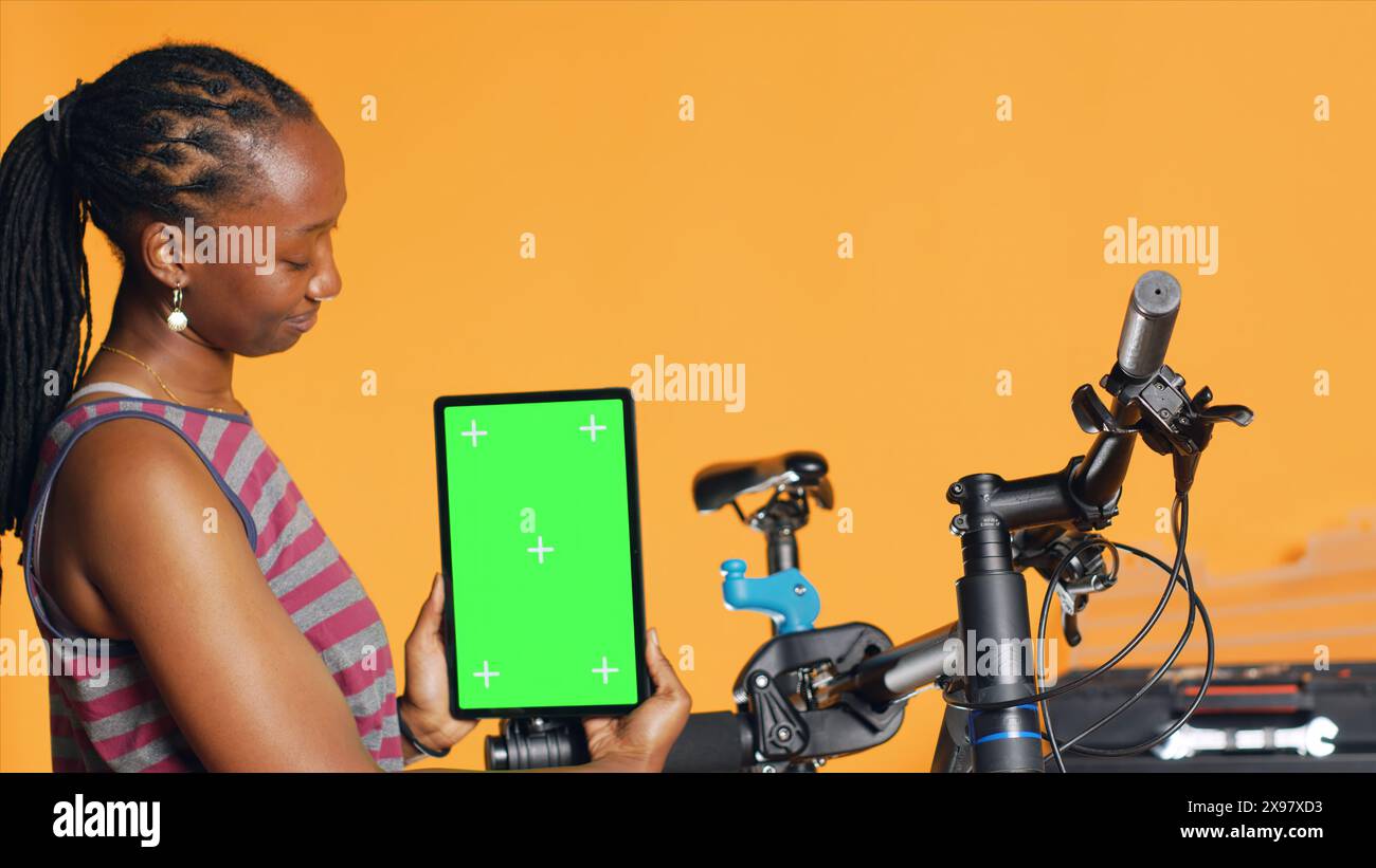 Woman holds green screen tablet, using it to advertise bike repair shop ...