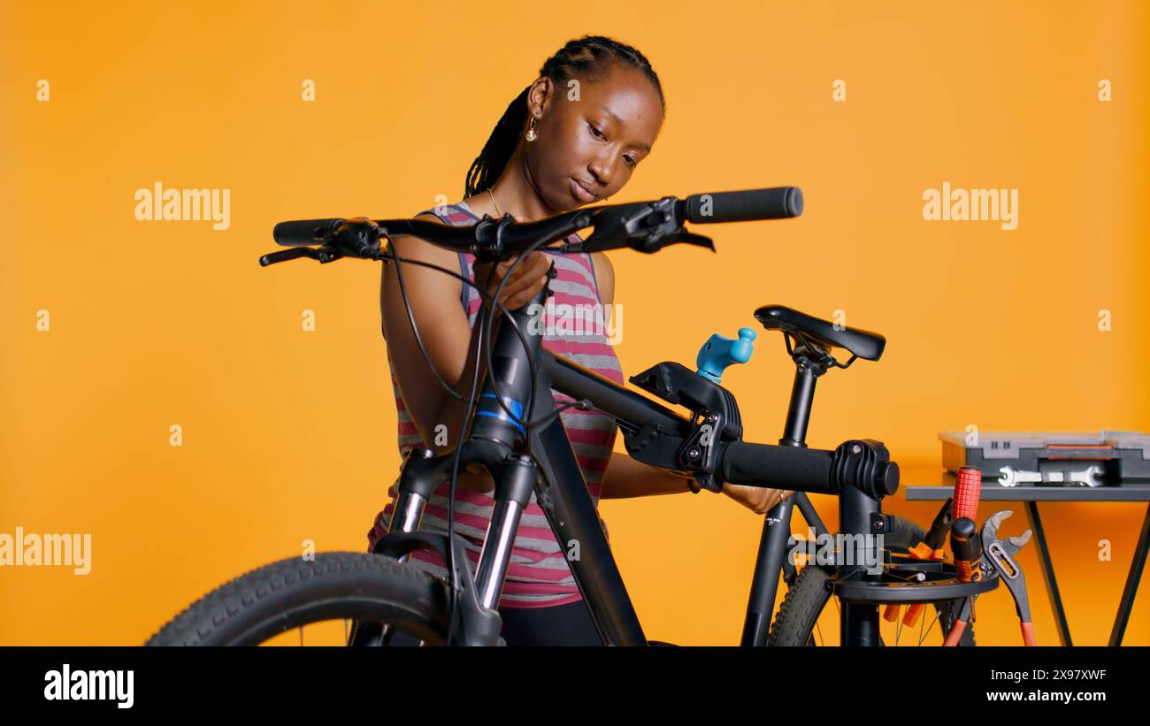 BIPOC mechanic setting up bike repair stand, using it to adjust ...