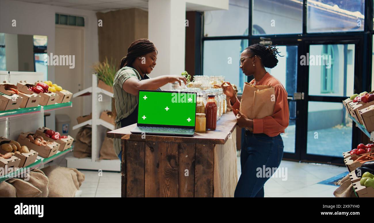 Vendor presenting eco goods on shelves next to greenscreen, recommends ...