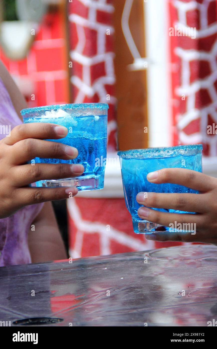 Two young brunette Latin women of 20 years old drink frosty blue ...