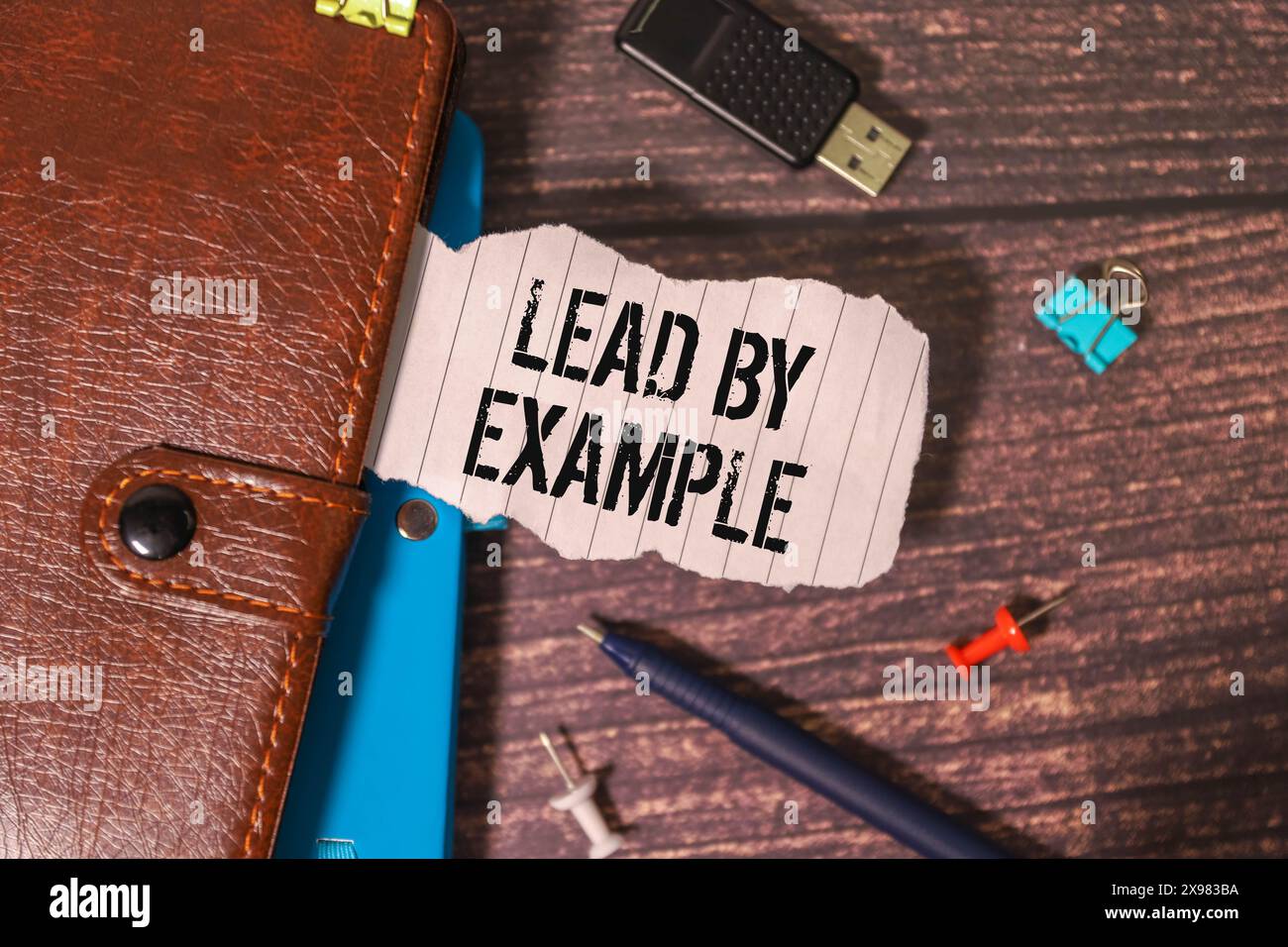 LEAD BY EXAMPLE text on a clipboard paper with laptop, mouse and pen ...