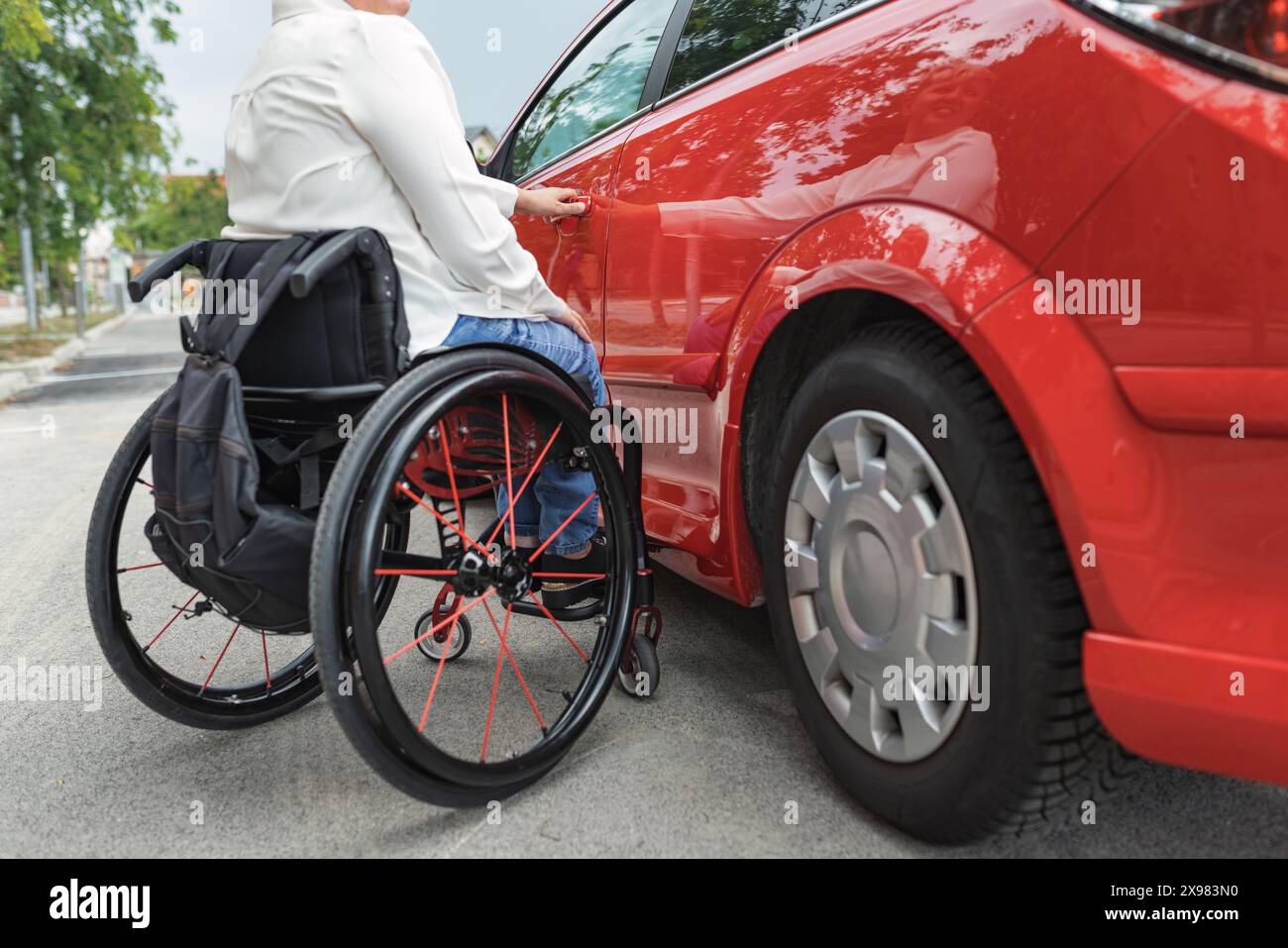 Female driver with disability entering a car, a wheelchair user on the ...