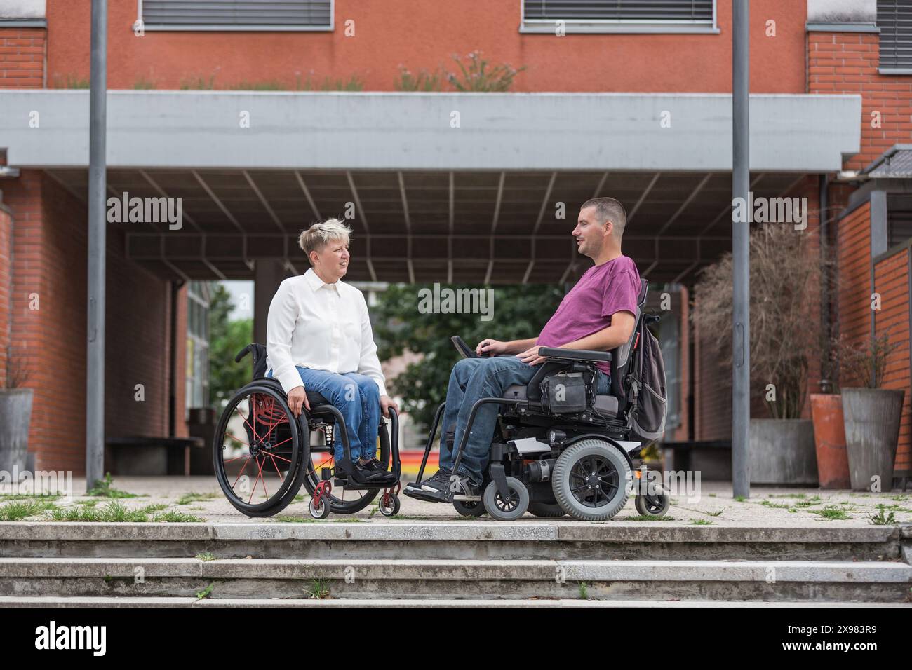 Two friends a woman and a man, wheelchair users spending time outdoors ...