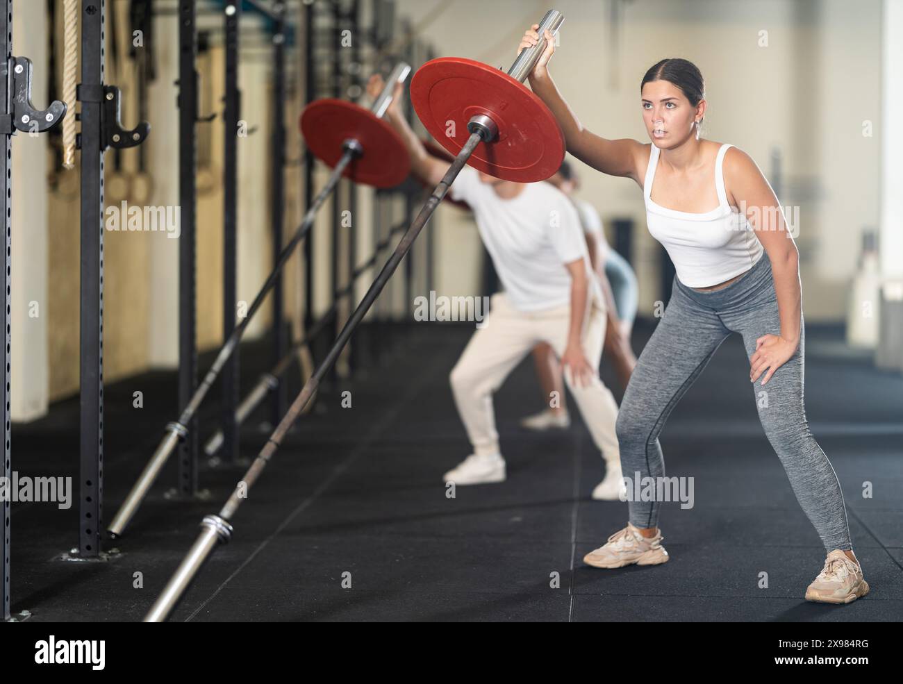 Athletic young woman pumping up her arm biceps using one side of ...