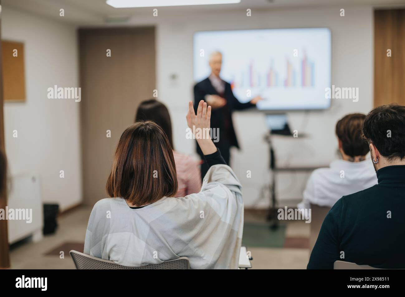 Back view of participants raising hands in an interactive session at a ...