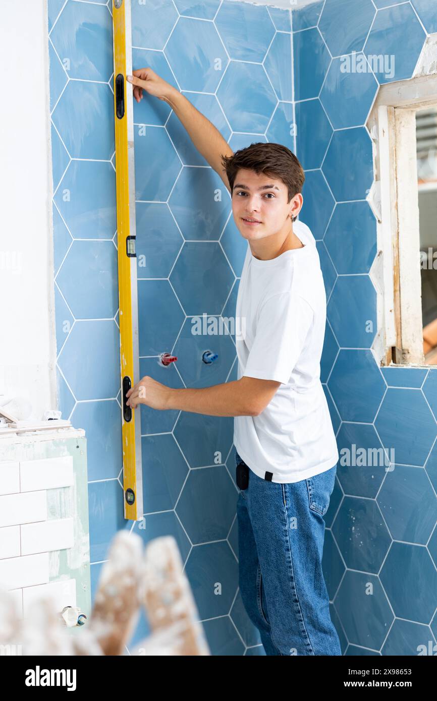 Guy inspecting quality of tiles laid on walls with level meter Stock ...