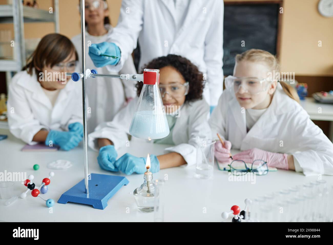 Group of ethnically diverse middle school students wearing lab coats ...