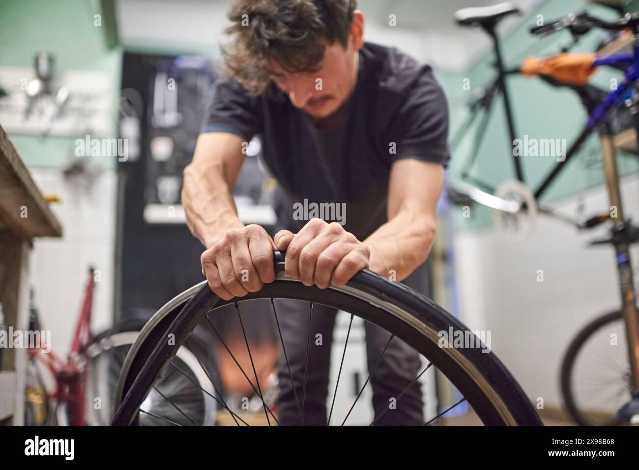 Hispanic bicycle repairman mounting an airless solid tire on a bike ...