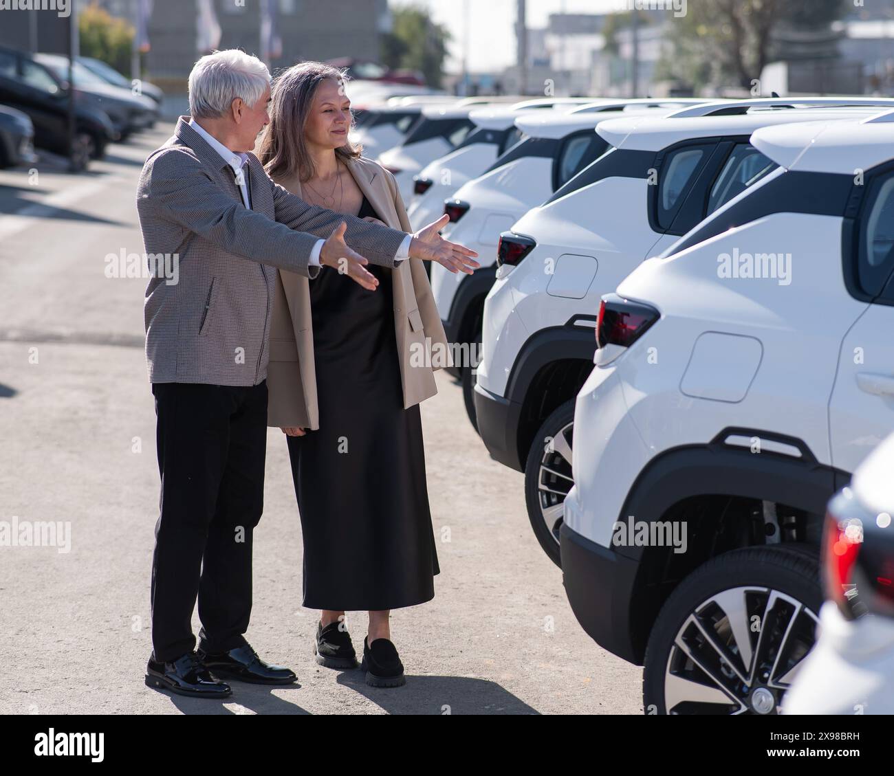 Mature Caucasian Couple Walks Past Cars Outdoors Choosing A New One