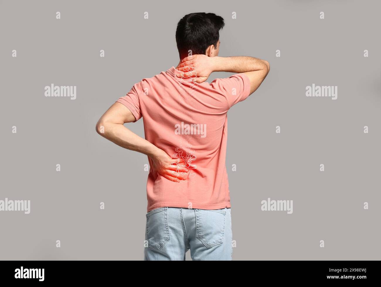 Young man suffering from back pain on grey background Stock Photo - Alamy