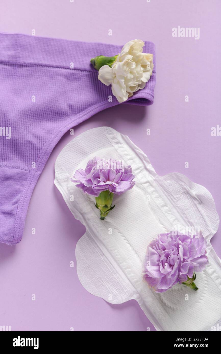Menstrual pad with carnation flowers and underpants on purple ...