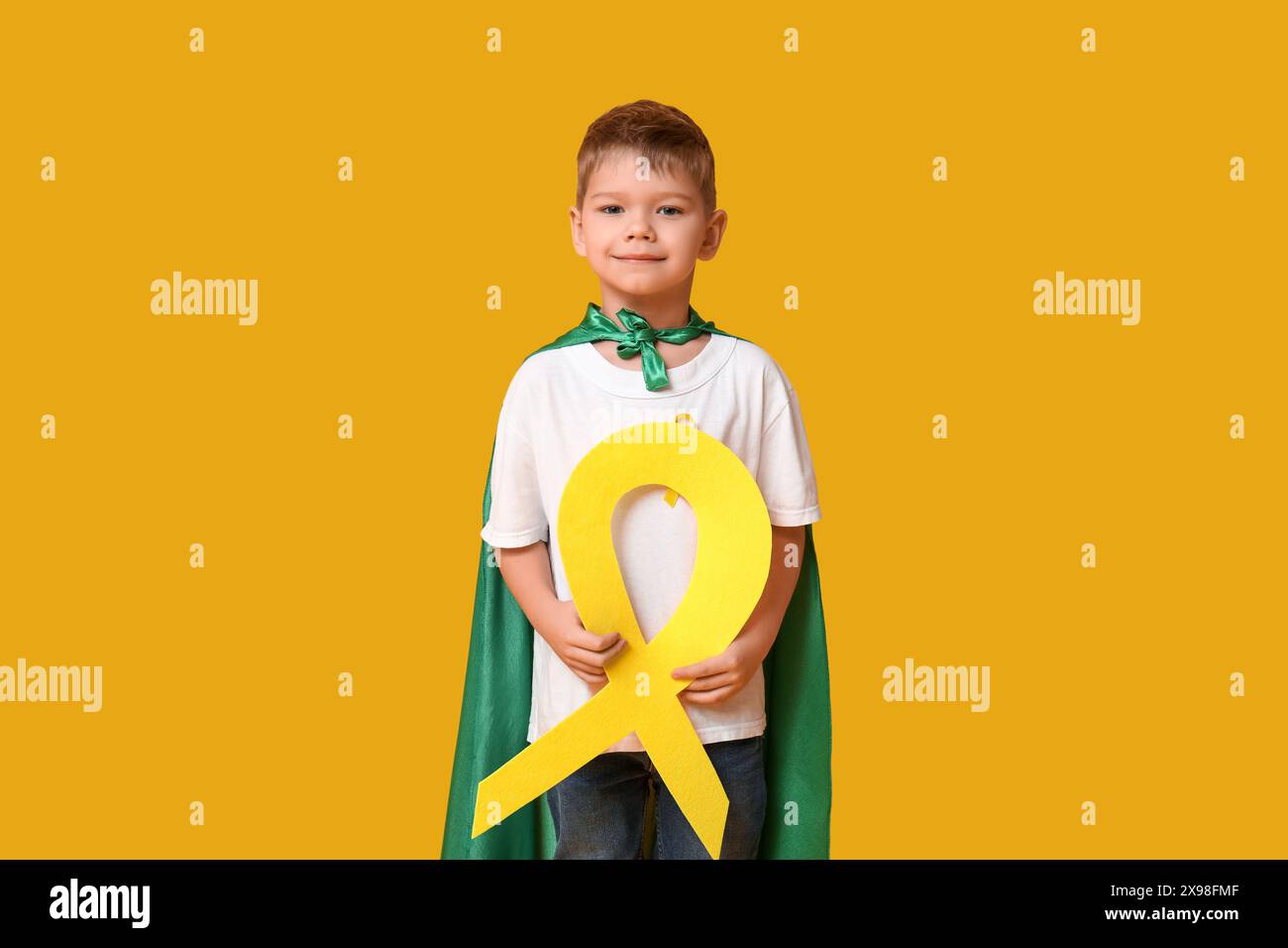Cute little boy in superhero costume with yellow ribbon on color ...
