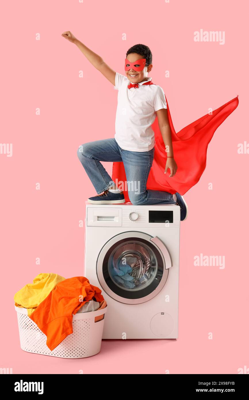 Little African-American boy in superhero costume on washing machine ...