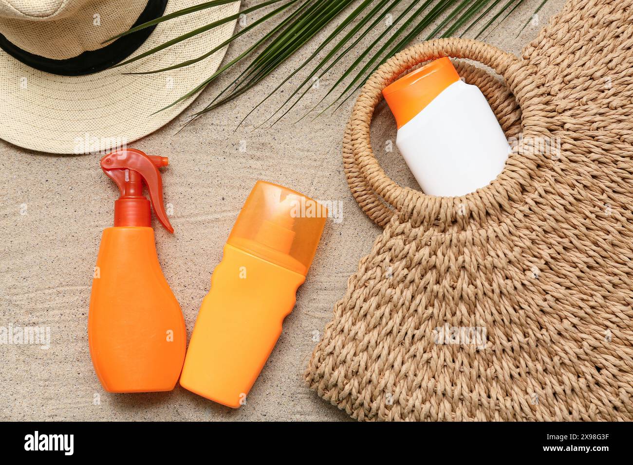 Beach bag with bottles of sunscreen on sand background Stock Photo - Alamy