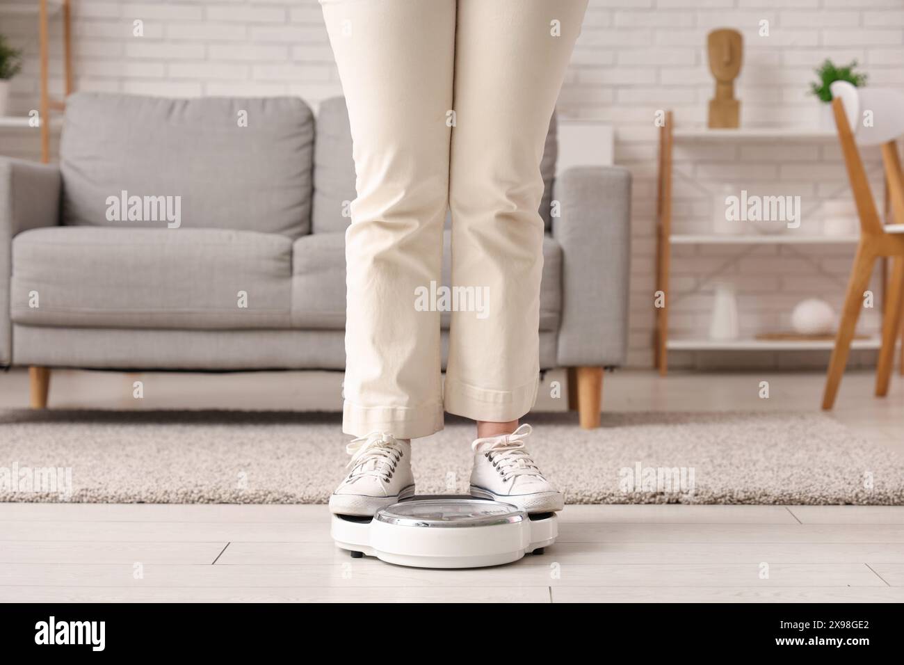 Young woman measuring weight on scales at home, closeup. Weight gain ...