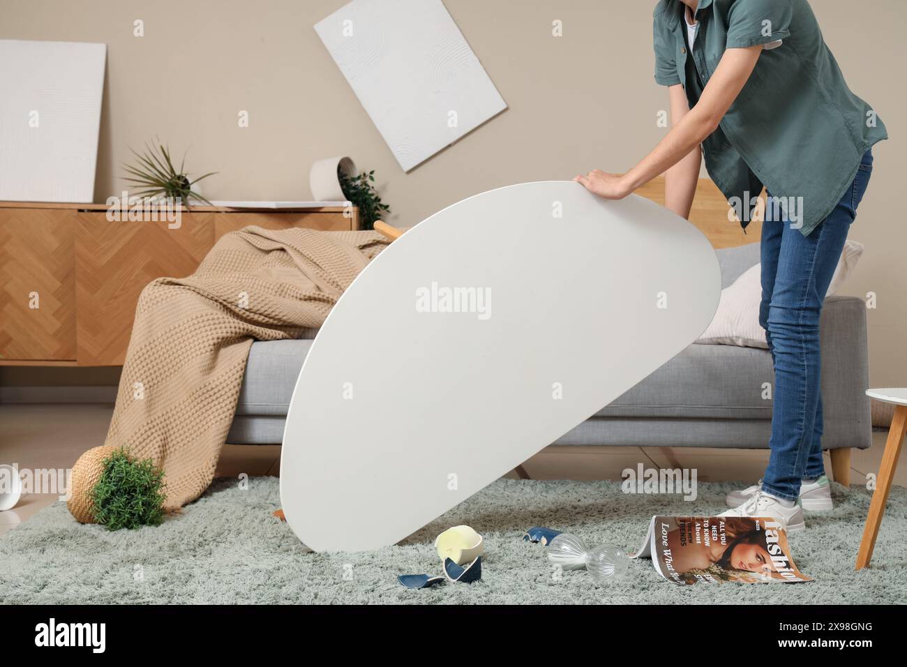 Woman taking overturned table after earthquake at home Stock Photo - Alamy