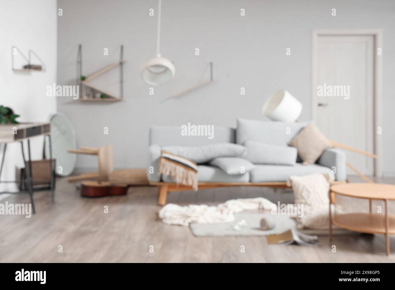 Blurred view of messy living room with sofa, shelves and tables Stock ...