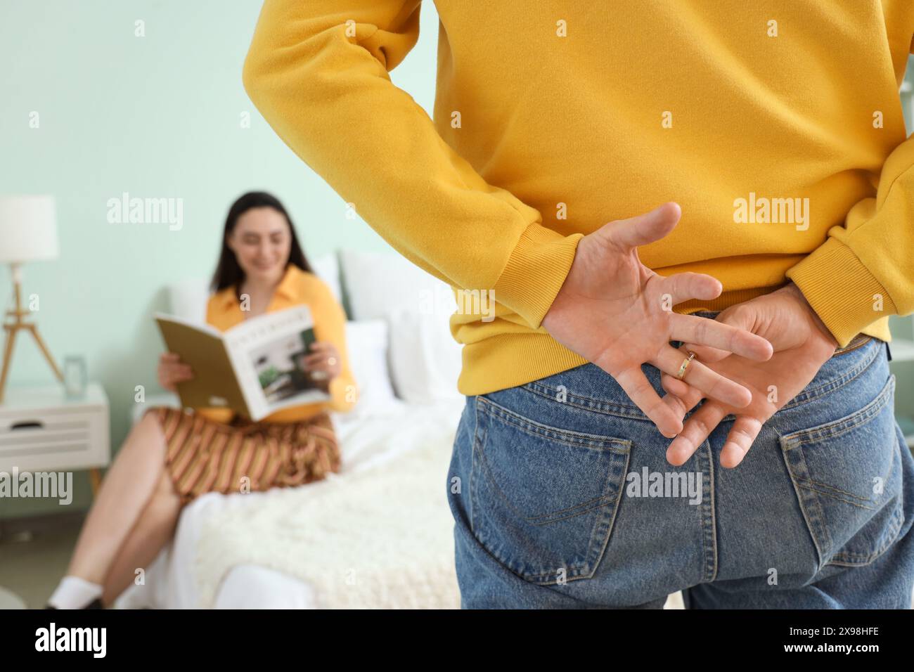 Young man taking her wedding ring off finger in bedroom, back view ...
