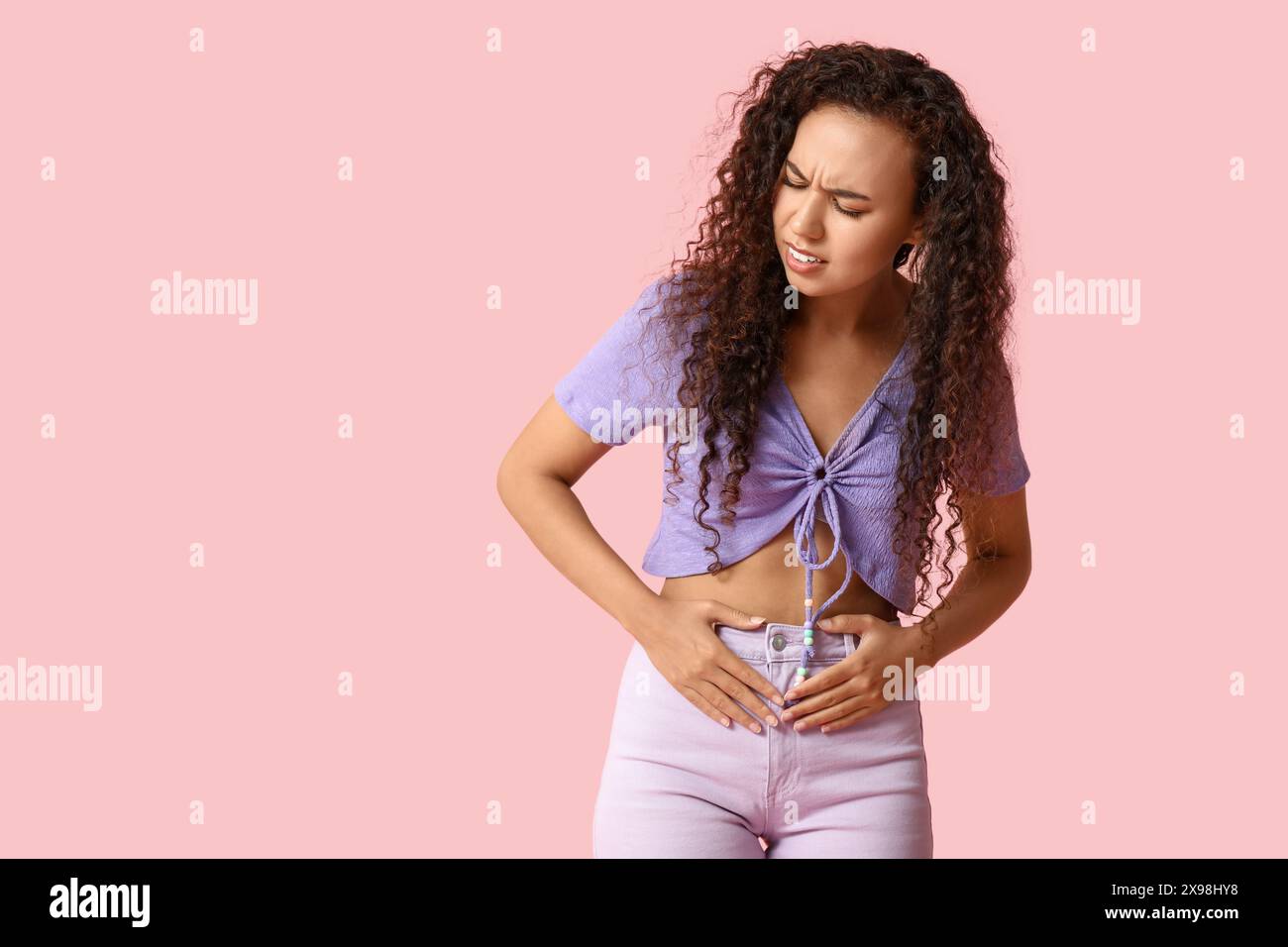 Young African-American woman with stomach ache on pink background Stock ...